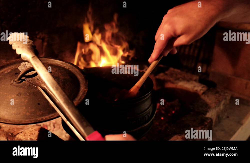 Stirring a potjie pot with a wooden spoon cooking on an open fire Stock ...