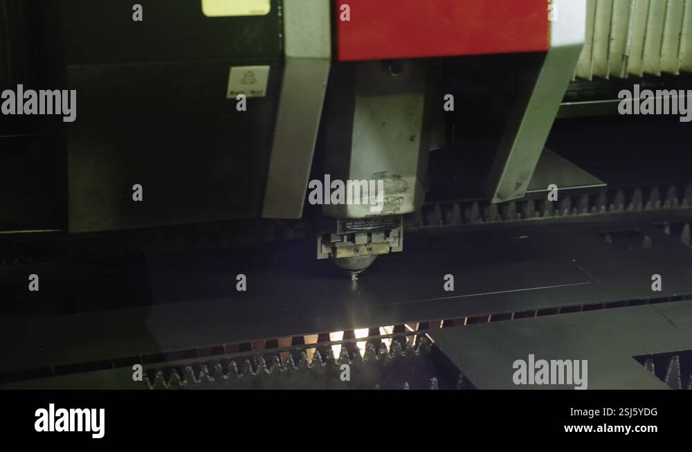 Automated laser cutter cutting a thin piece of metal in a factory ...