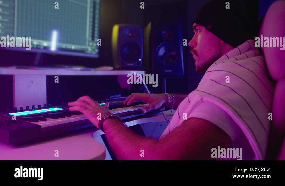 Music maker creating track in studio using synthesizer and computer ...