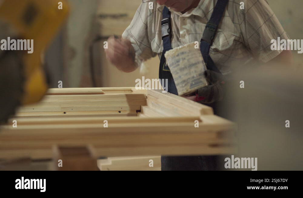 Carpenter is staining the wooden window frame using white paint in the ...