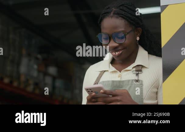 Slow motion close-up shot of African American roaster in apron smiling, while texting on her ...
