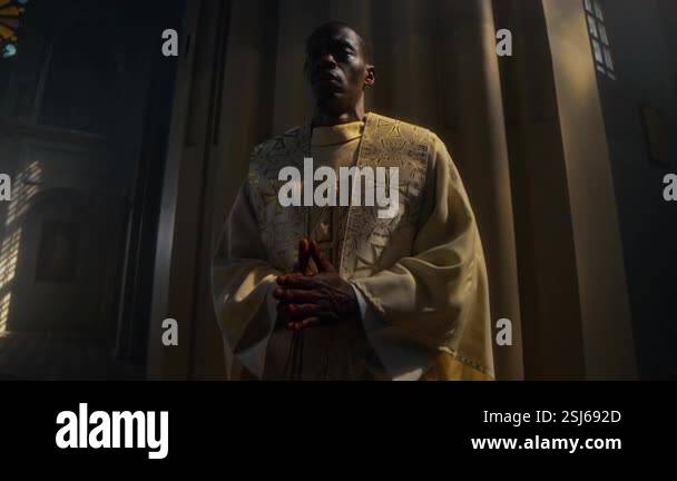 View from below of African American priest dressed in golden white robe ...