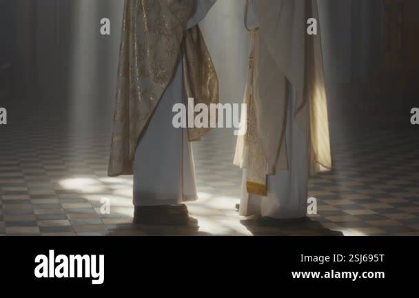 Tilt up view of two diverse catholic priests reciting prayers standing ...