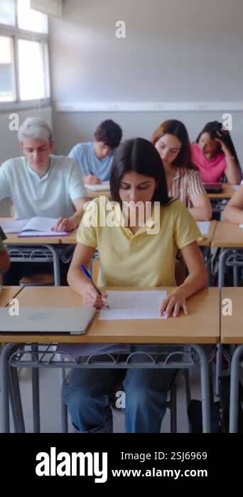 Vertical. Front view of a group of multiracial students working together in a classroom. The ...