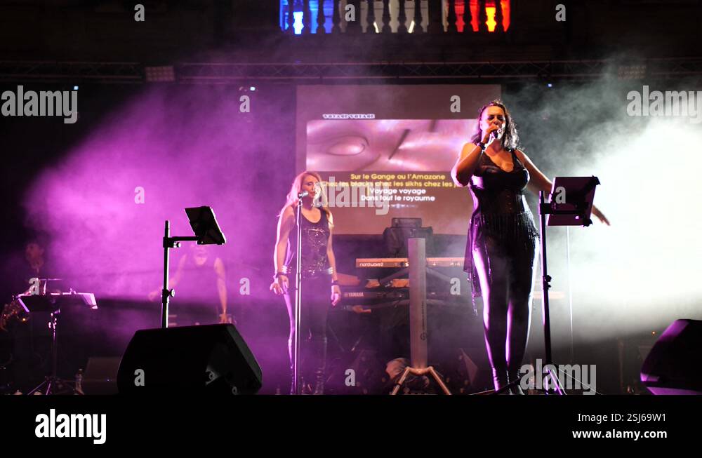 Two female singers on stage singing in purple and white smoke, one ...