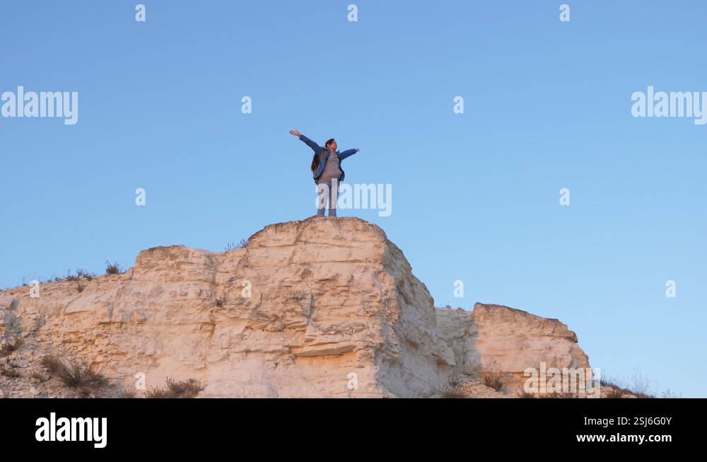 Free woman tourist stands on edge of cliff. Girl hiker on top of cliff ...