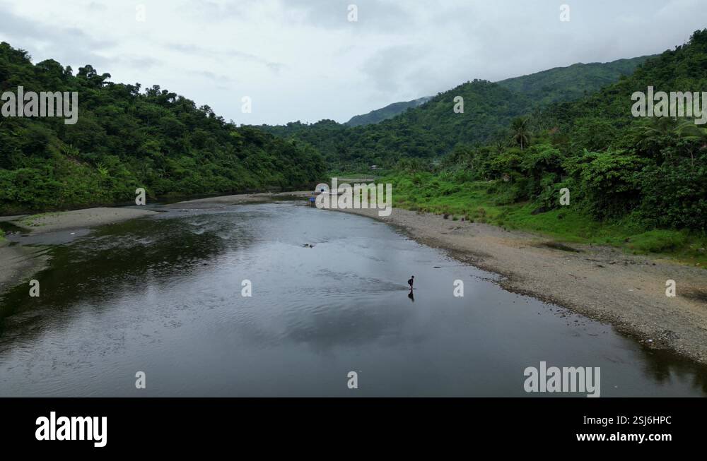 Wide Aerial View of a Young Child wearing a backpack crossing a shallow ...