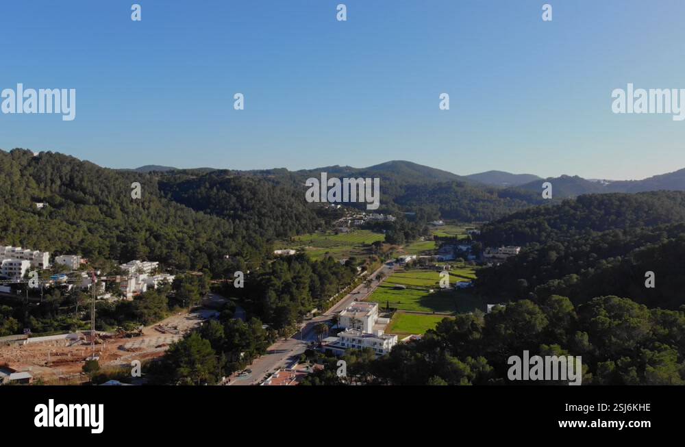 Drone moving forward on ibiza by a road leading down to a small beach ...
