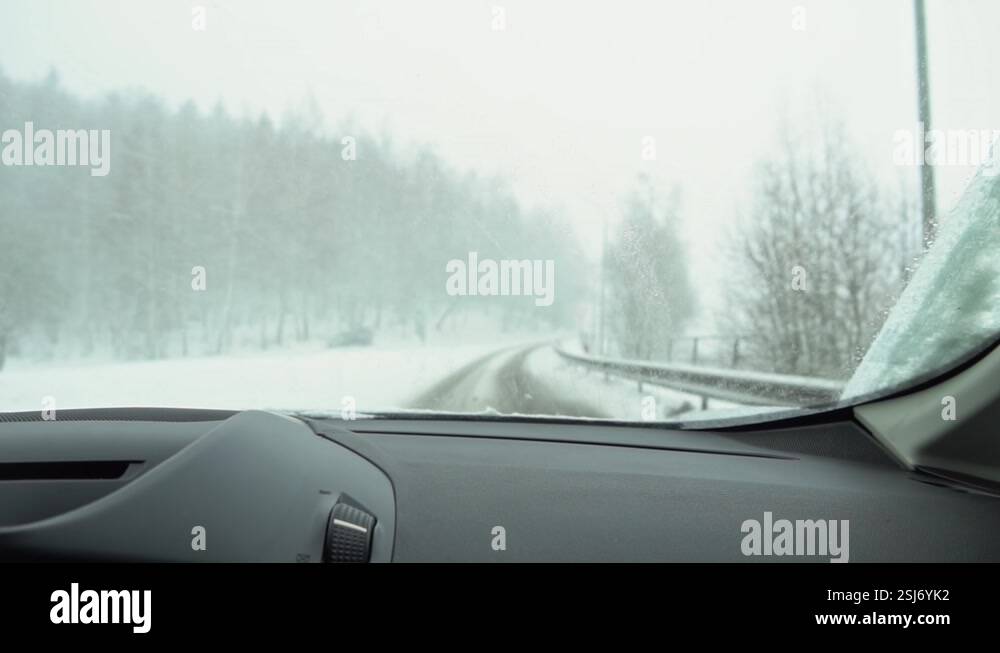 View from the windshield of a car that is driving along a snowy rural ...