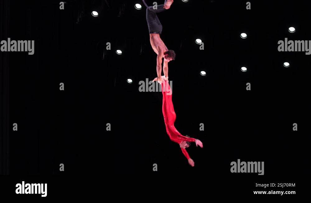 Circus aerial hoop duo with on black stage background performing trick ...