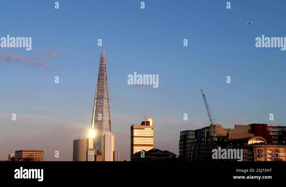 Sun reflecting in the glassed facade of The Shard while a plane flights ...