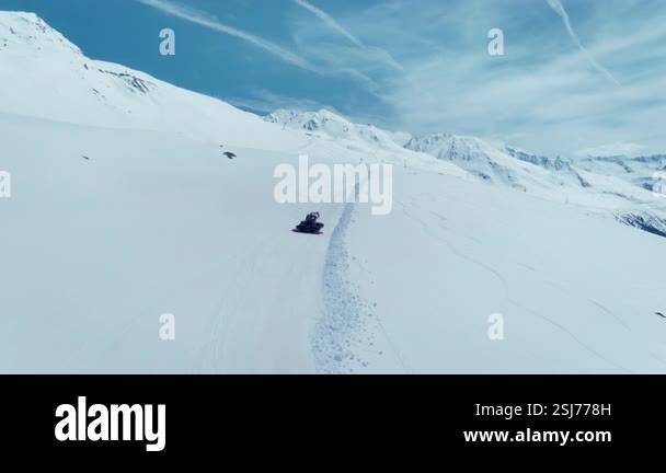Drone follows snowcat plowing snow on ski slopes of ski resort on sunny ...