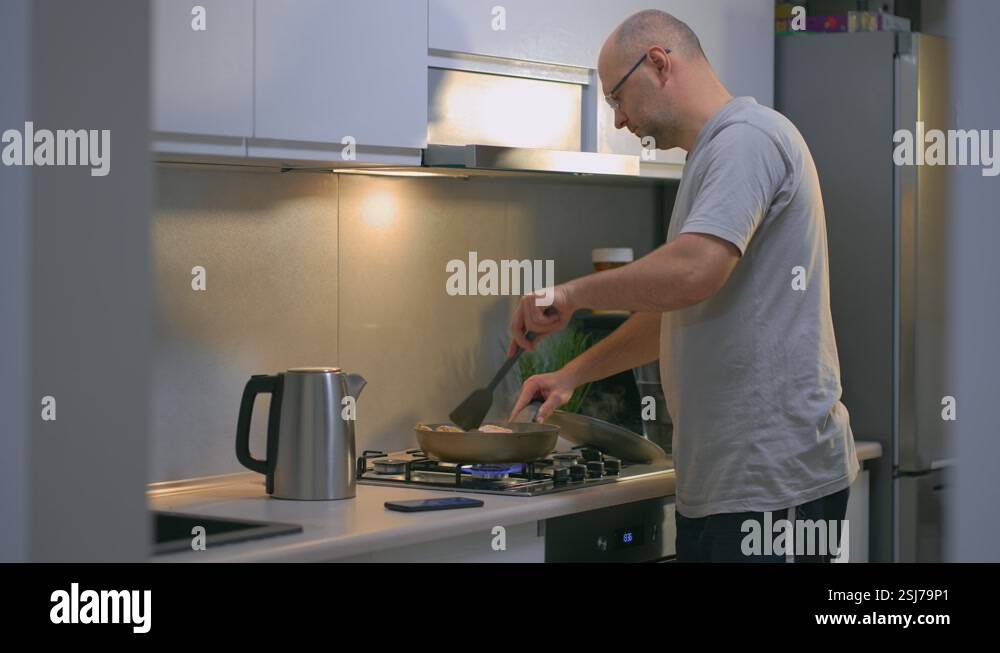 Man cooking fried chicken meat in pan in kitchen for family dinners ...