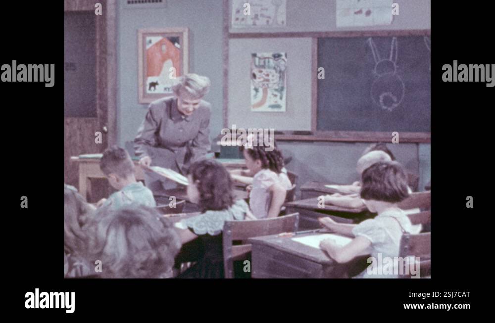 1950s:Man holds up film slate. Teacher in classroom looks at paper with ...