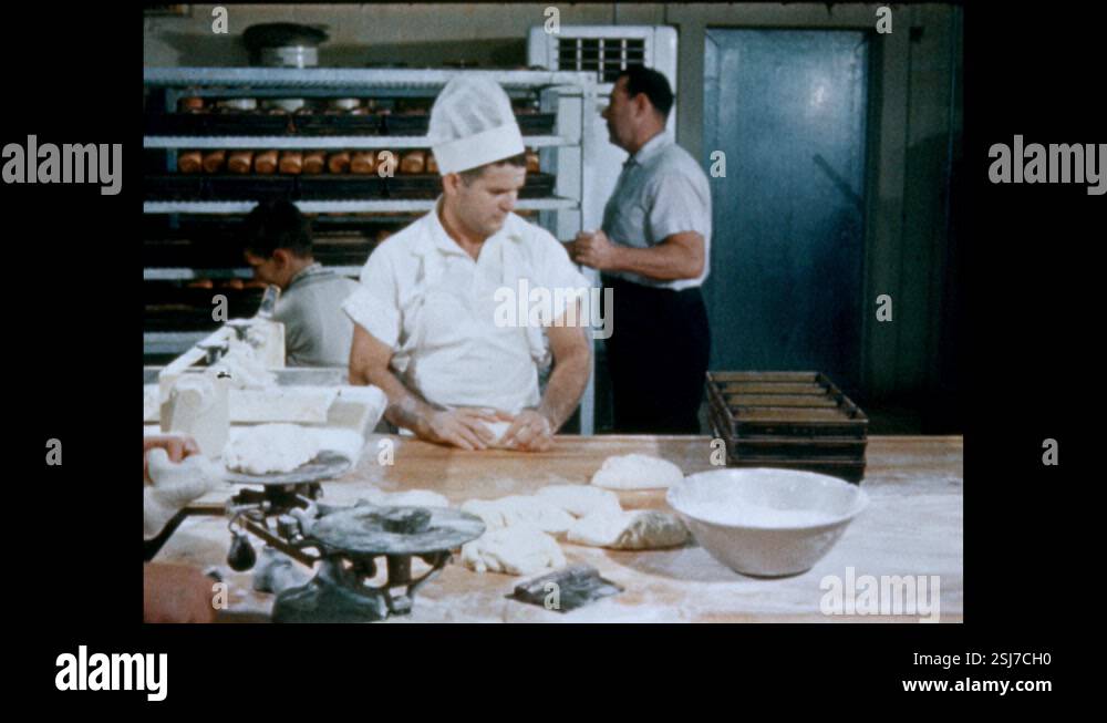 1960s:Man shows boy oven where bread is baked. Hands place bread loaves ...