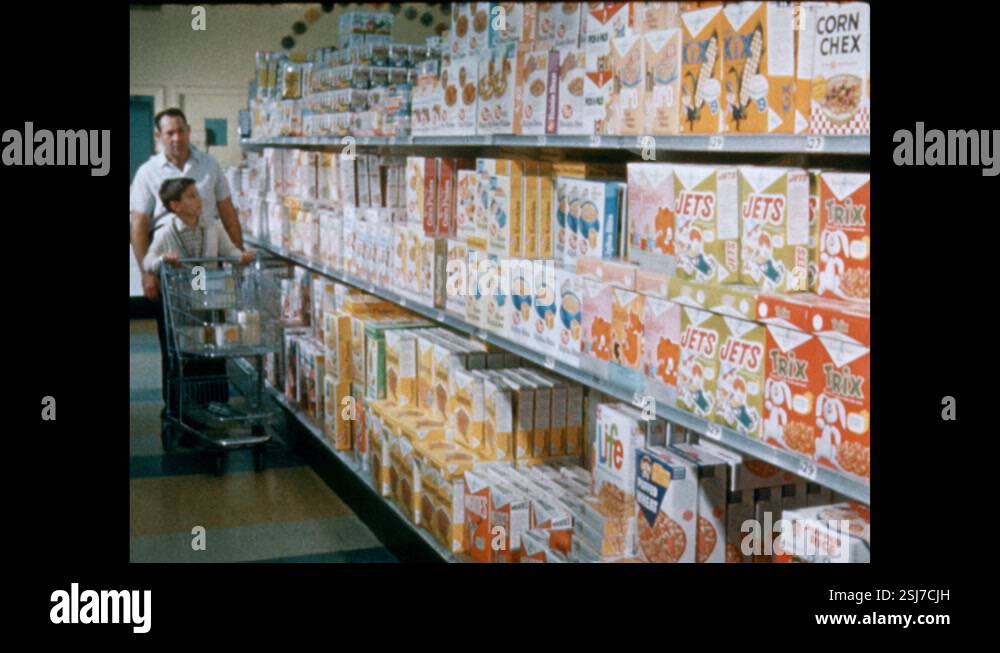 1960s:Man and boy at the grocery store. Boy puts oats into the cart ...