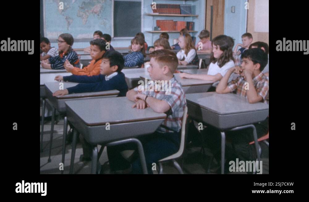1960s: children sit at school desks in rows in classroom, some with ...
