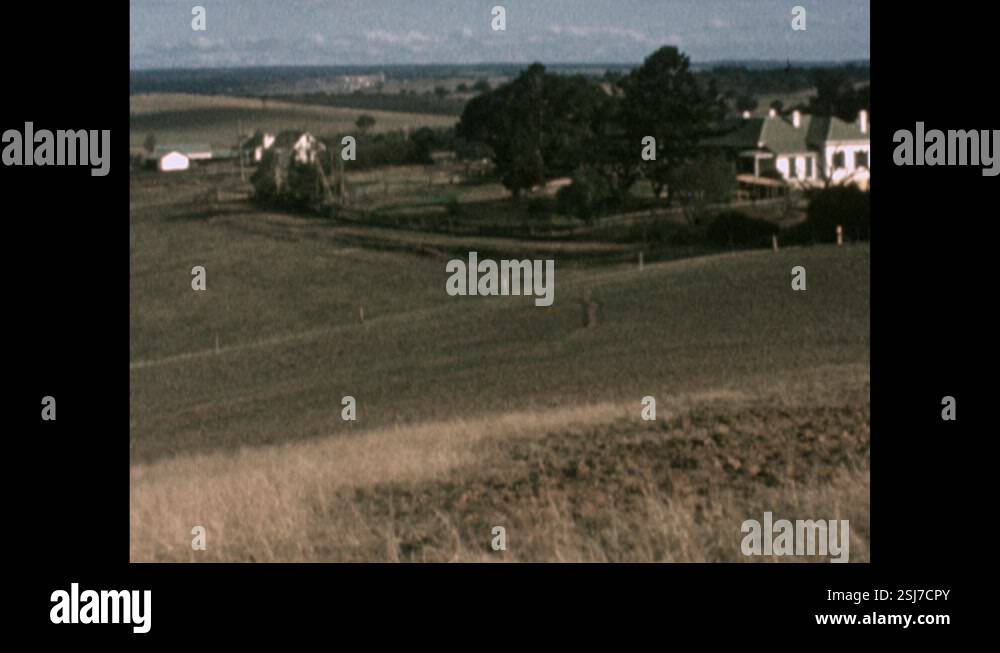 1950s: Film slate. Houses and fields in the rolling hills. Farm fields ...