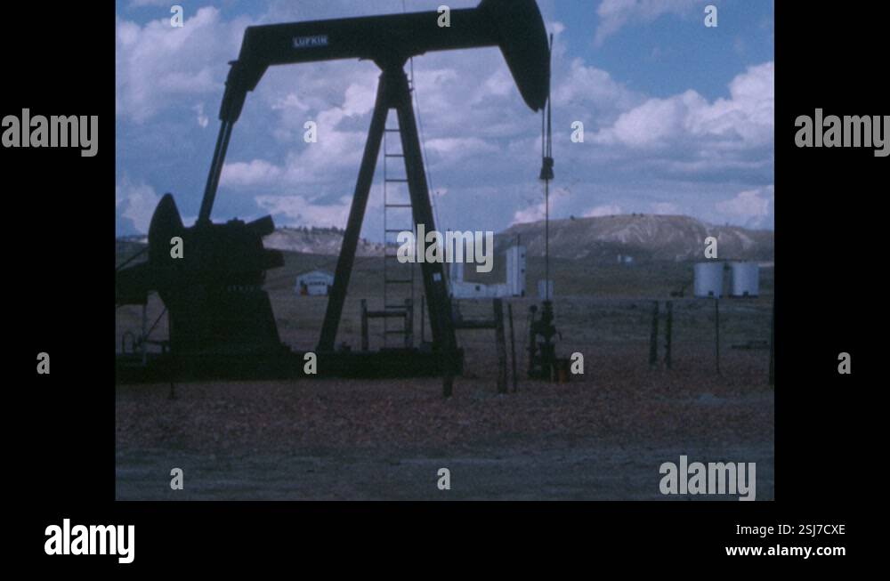 1960s: Oil well drilling. Hand over lens, pan across mountains, forest ...