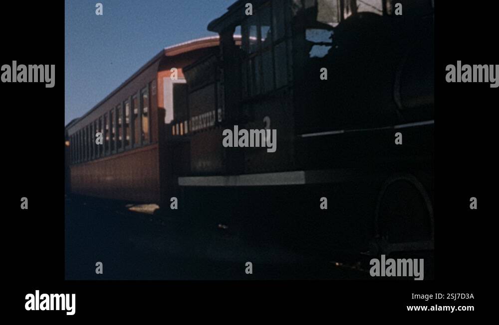1950s: Locomotive and passenger cars pulling away. Man in top hat. Part ...