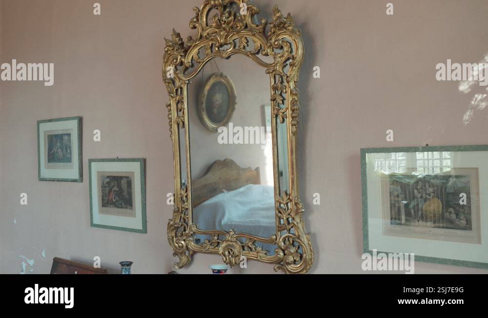 Slow rotating shot of a gilt-edged mirror hanging on a wall beside ...