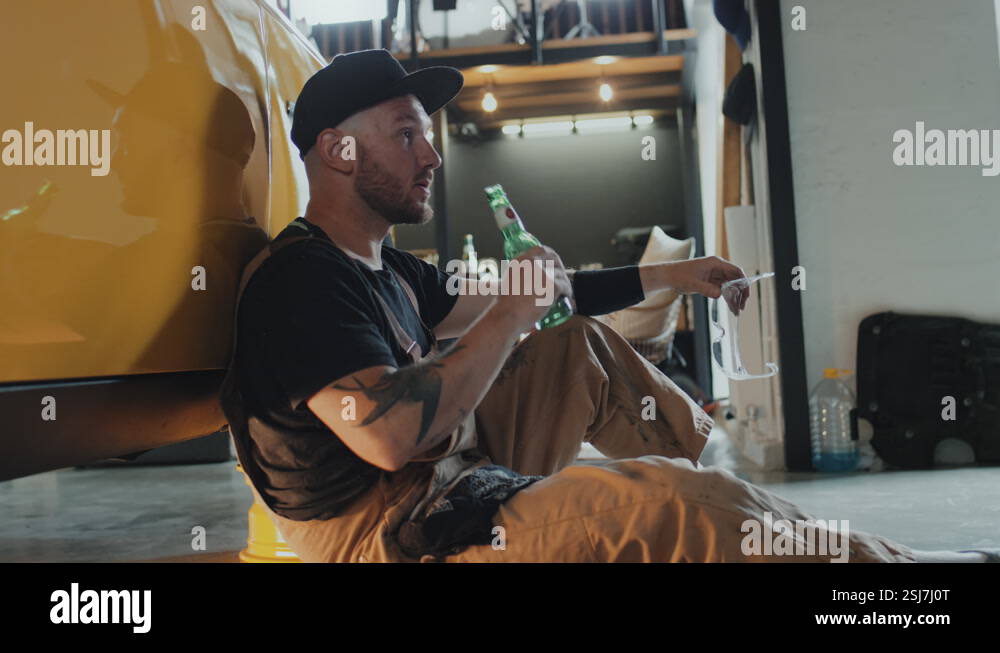 Auto Mechanic Sitting Beside Yellow Car, Taking Beer Bottle, Making Sip ...