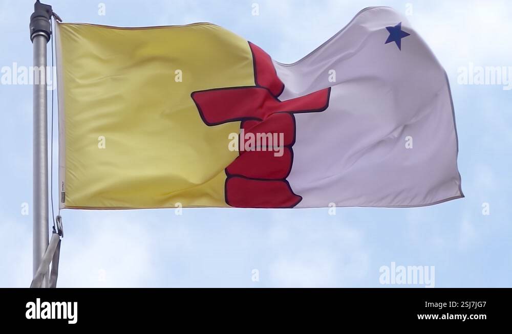 A waving of the Flag of Nunavut, a red inuksuk a traditional Inuit land ...