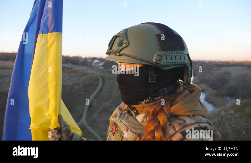 Young girl in military helmet and balaclava holds a waving national ...