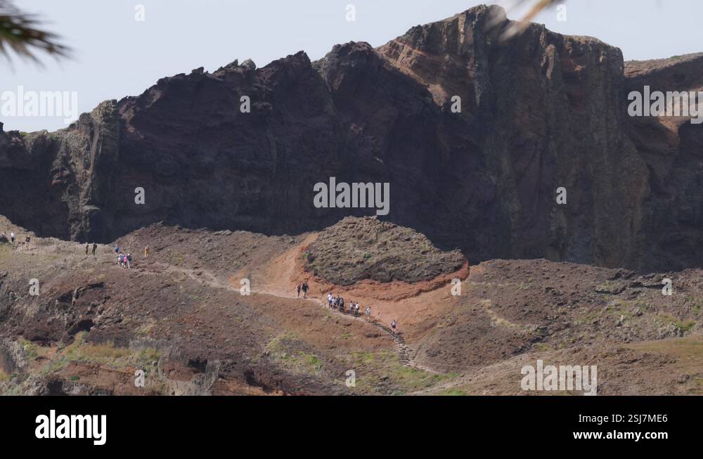 People wander on hiking trail by majestic cliff at Ponta de Sao ...