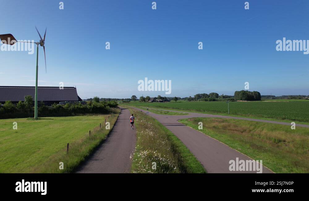 Dutch farmland aerial of river valley with trail runner followed from ...
