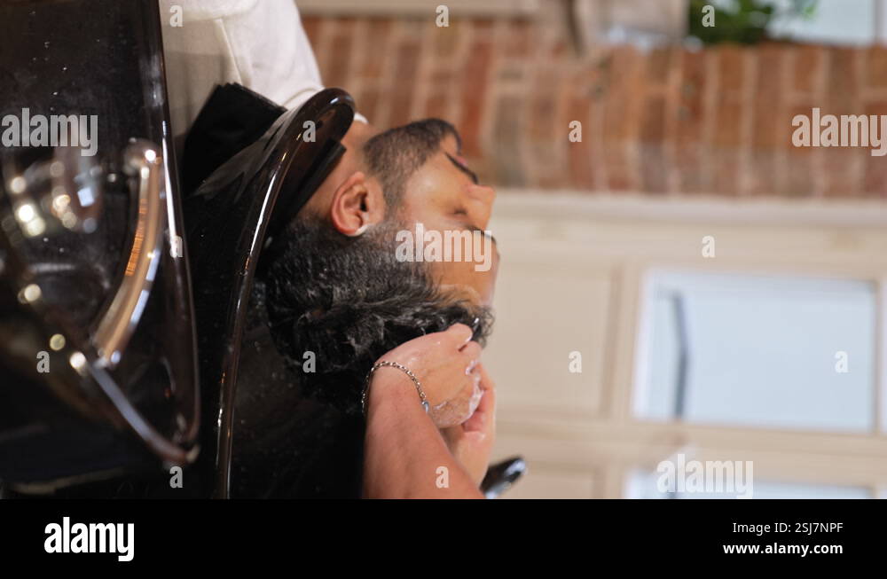 Barber hands massaging and shampooing male client hair before a haircut ...