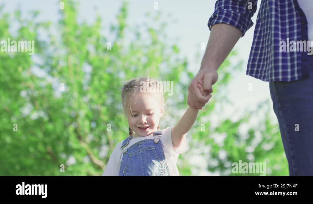 Dad, little daughter walk holding hands. People in park. Happy family ...