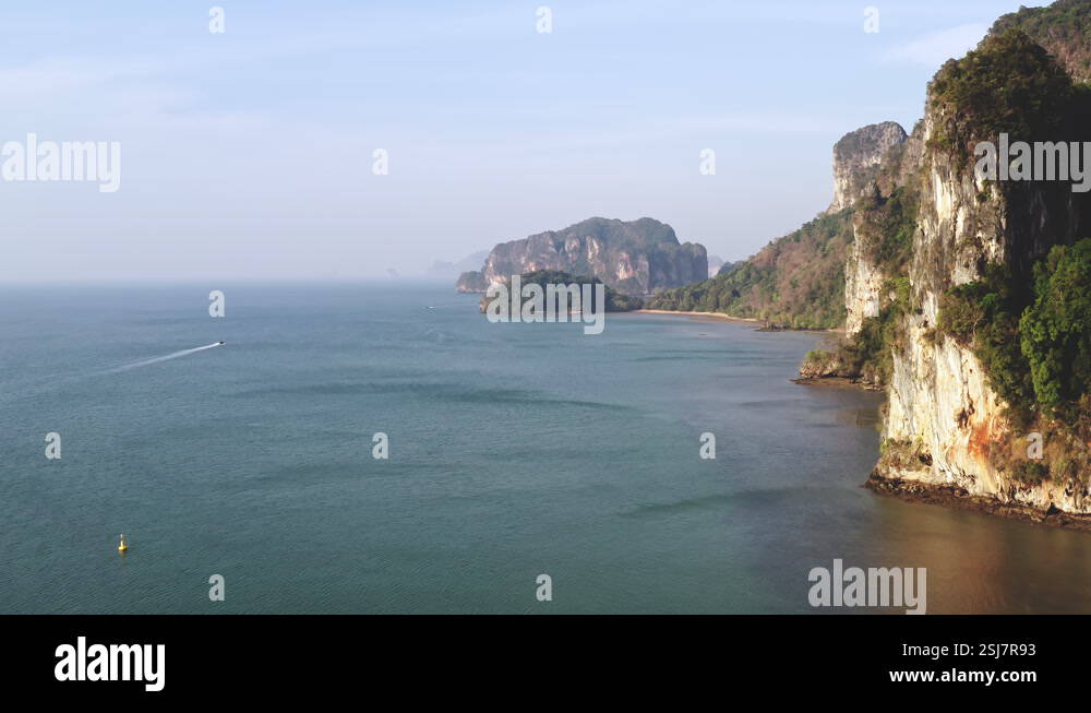 Massive coastal limestone cliffs in Andaman sea, boat cruising below ...