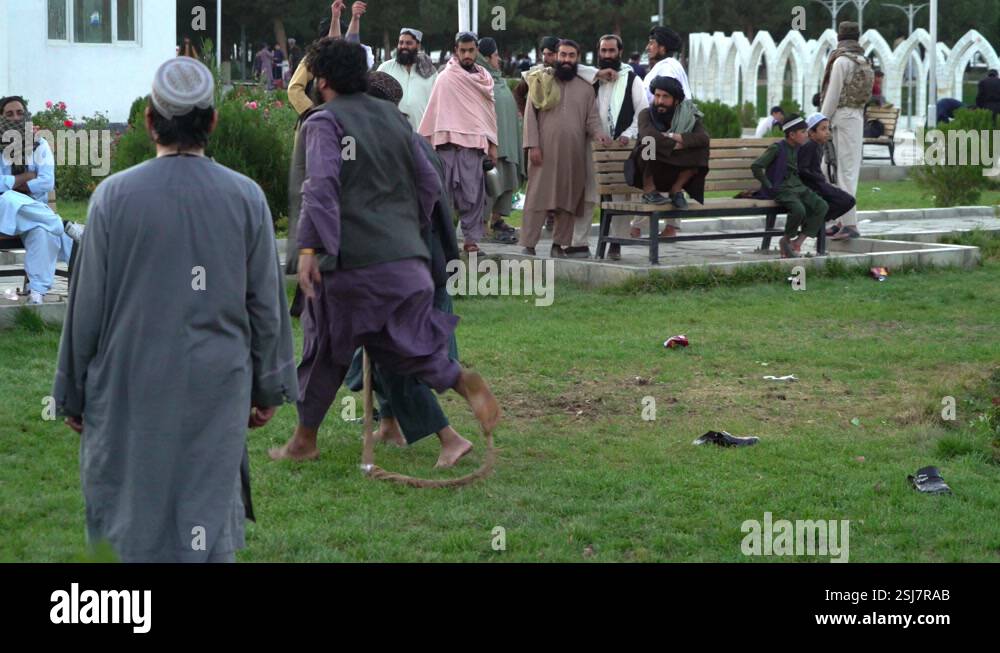 Men in traditional clothes play rope game Dora in park in Afghanistan ...