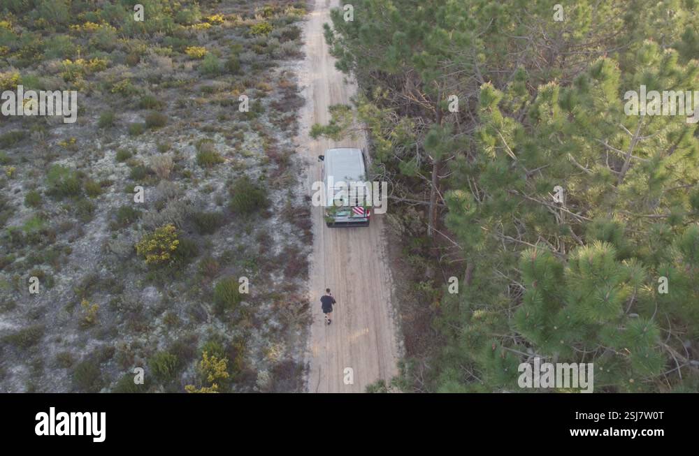 man running alongside a green travel camper van down a dirt road with a ...