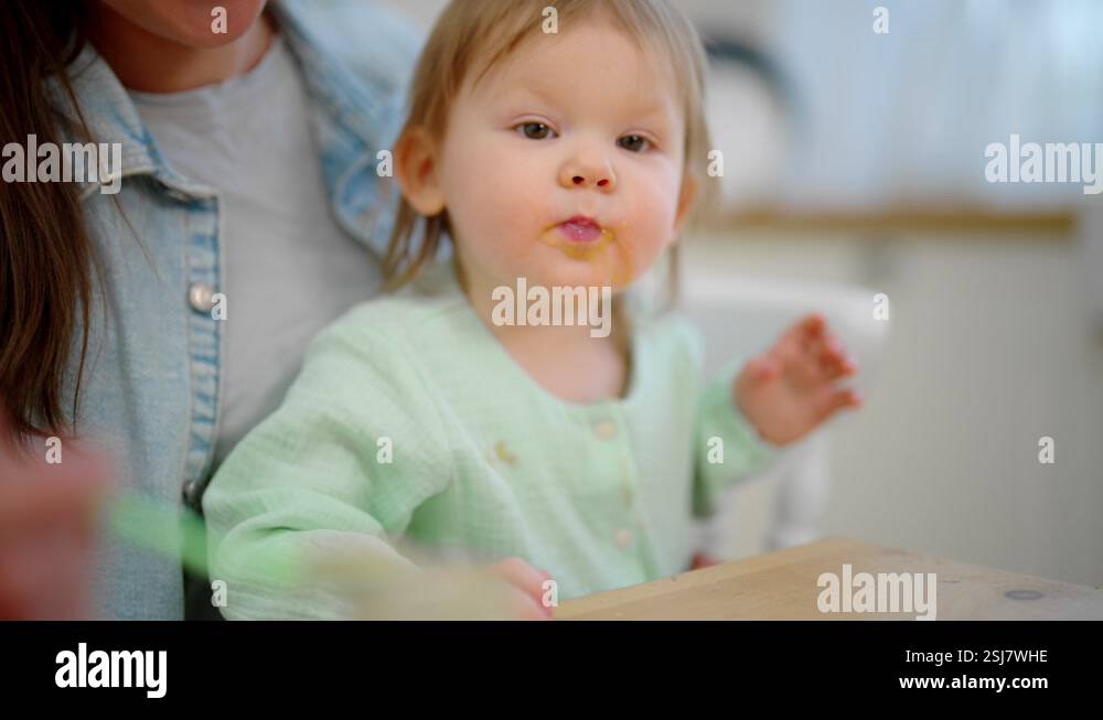 Mom feeding her baby with milk porridge at home. Portrait of baby ...
