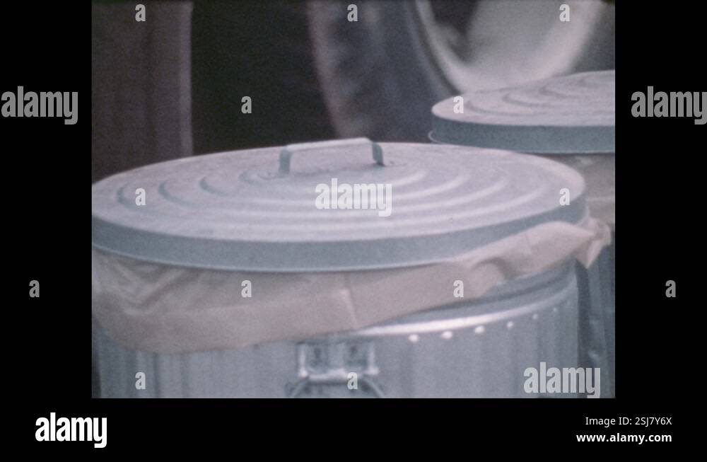 1970s: Film slate. Garbage collectors pick up garbage cans and throw ...