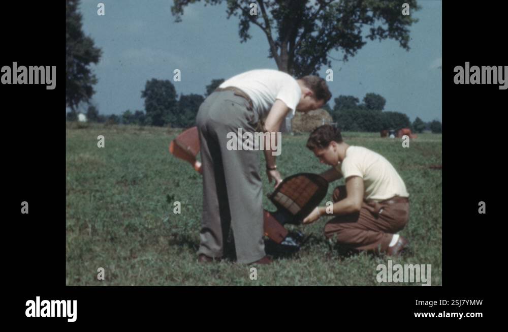 1950s: Model plane nose down in ground. Two boys run to plane and pull ...