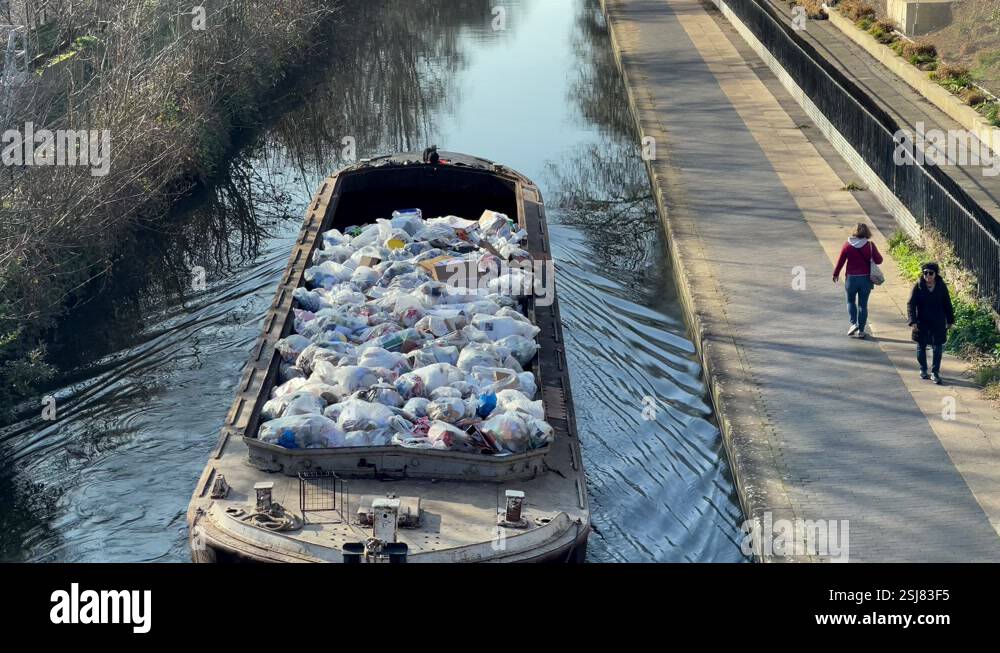 Narrow boat barge transporting trash cruising a river canal with some ...
