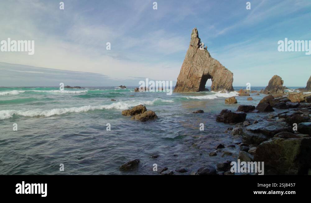Cinematic forward dolly of a wild pebble beach with sharp cliffs and a ...