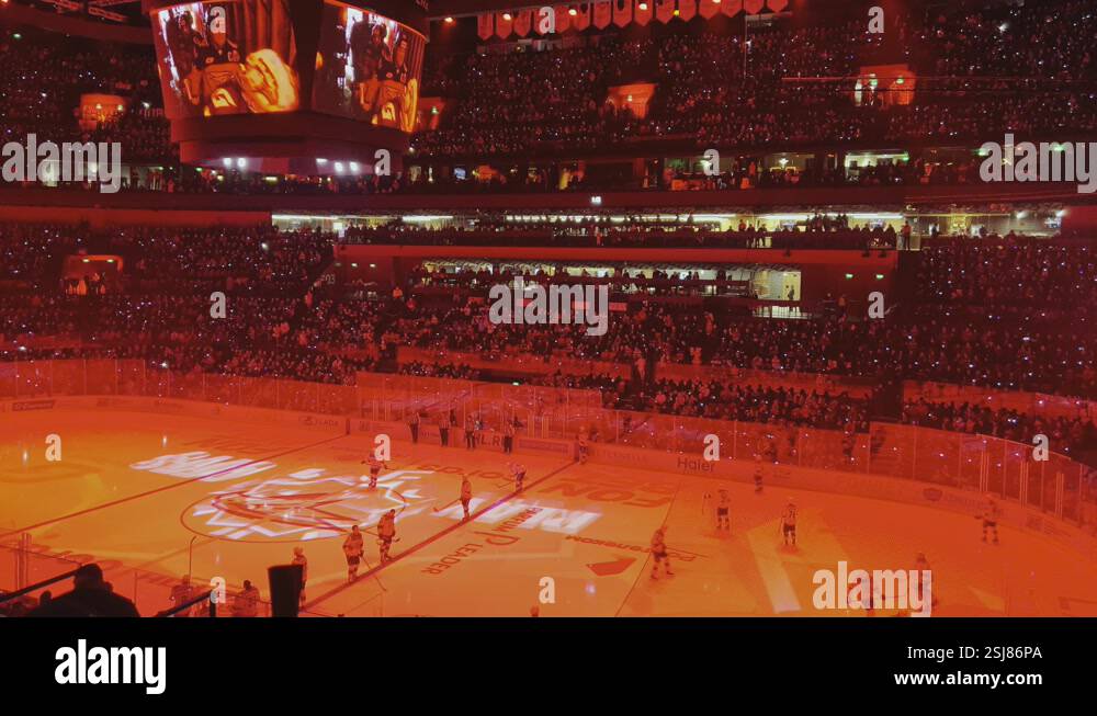 A sports stadium with an ice rink, flashing lights and cheering fans ...