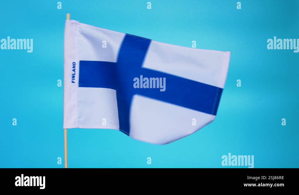 Flag of Finland. The flag of Finland flutters in the wind on a blue ...