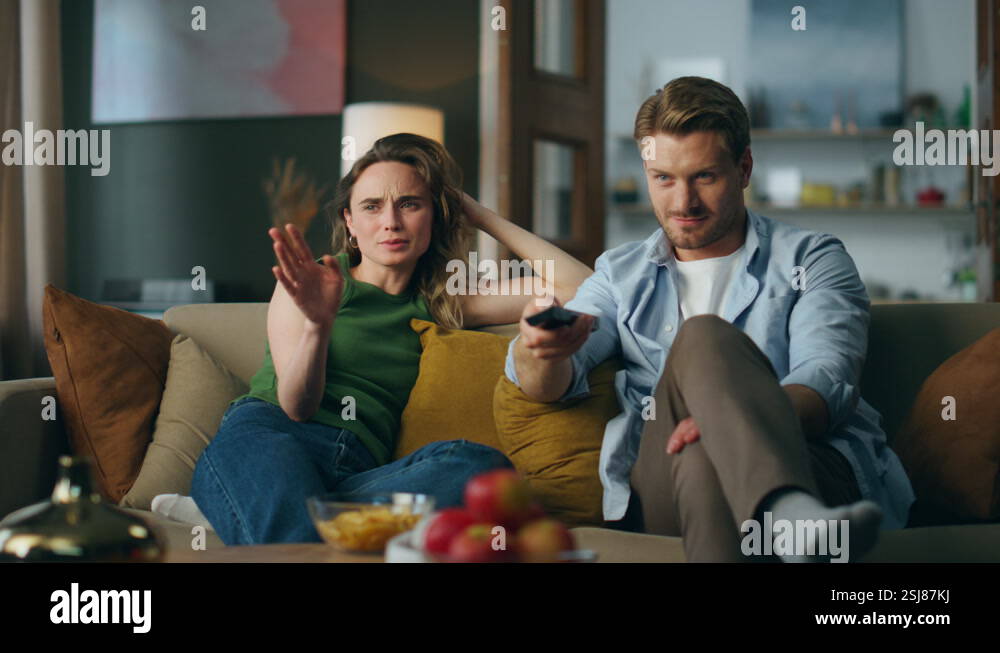 Relaxed partners chilling sofa watching tv evening. Smiling man turning ...