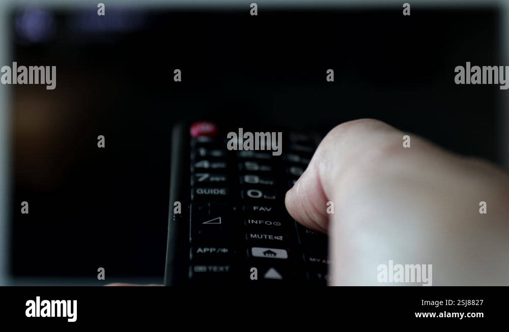 Close-up of a remote control held by a man while changing channels ...