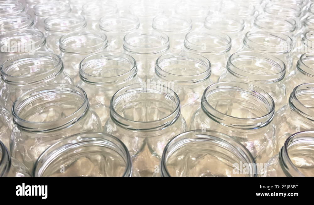 Rows of new clear glass jars for canning stand in the kitchen supply ...