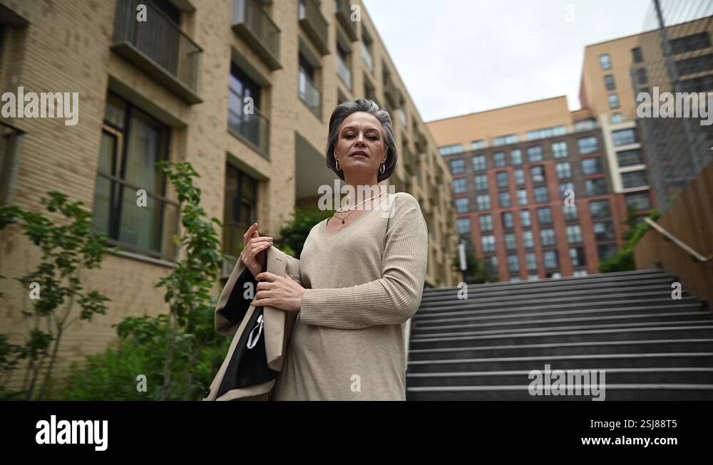 Elderly caucasian business woman takes off her jacket outdoors. Video ...