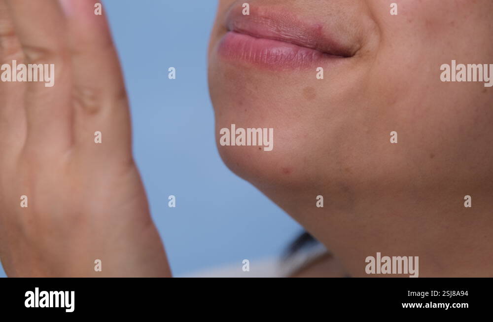 Young woman chewing gum and covering mouth to check breath with her ...