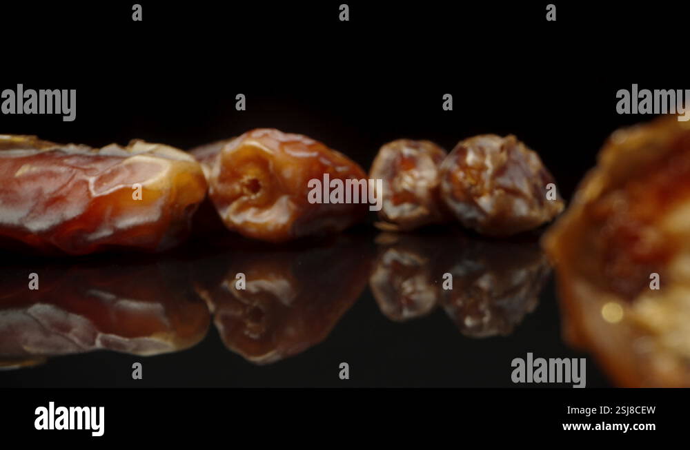 Dried dates on a black table, half with a stone, Dolly slider extreme ...