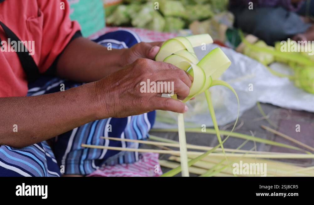 Woman's hand making ketupat rice cake using palm leaf for eid fitr ...