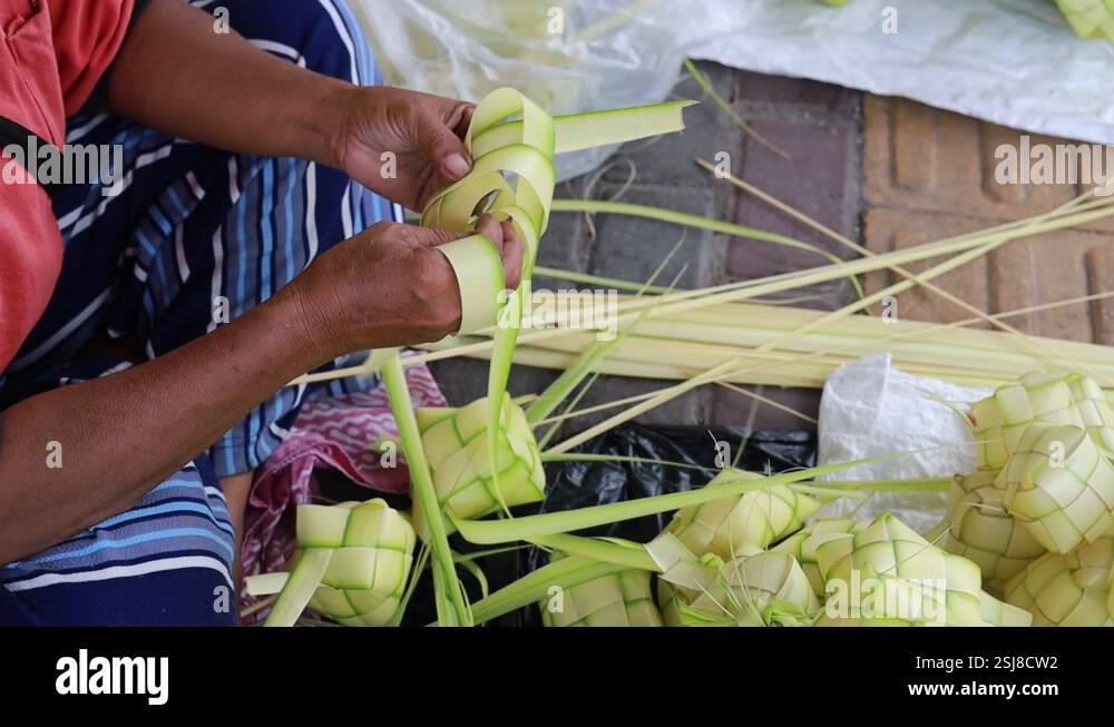 Top view of Woman's hand making ketupat rice cake using palm leaf for ...